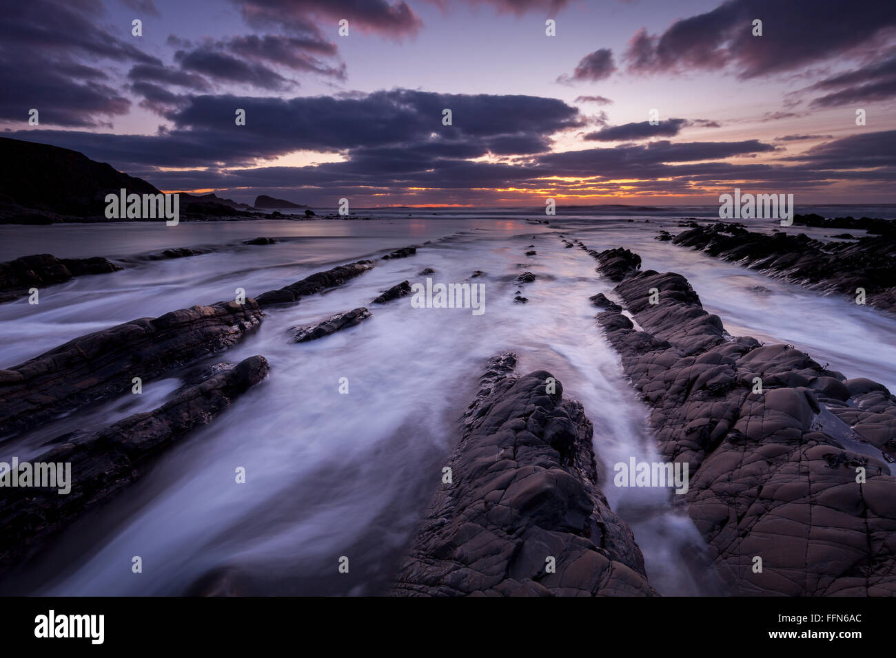 Waves flow over the rock formations at Welcombe Mouth Beach in North ...