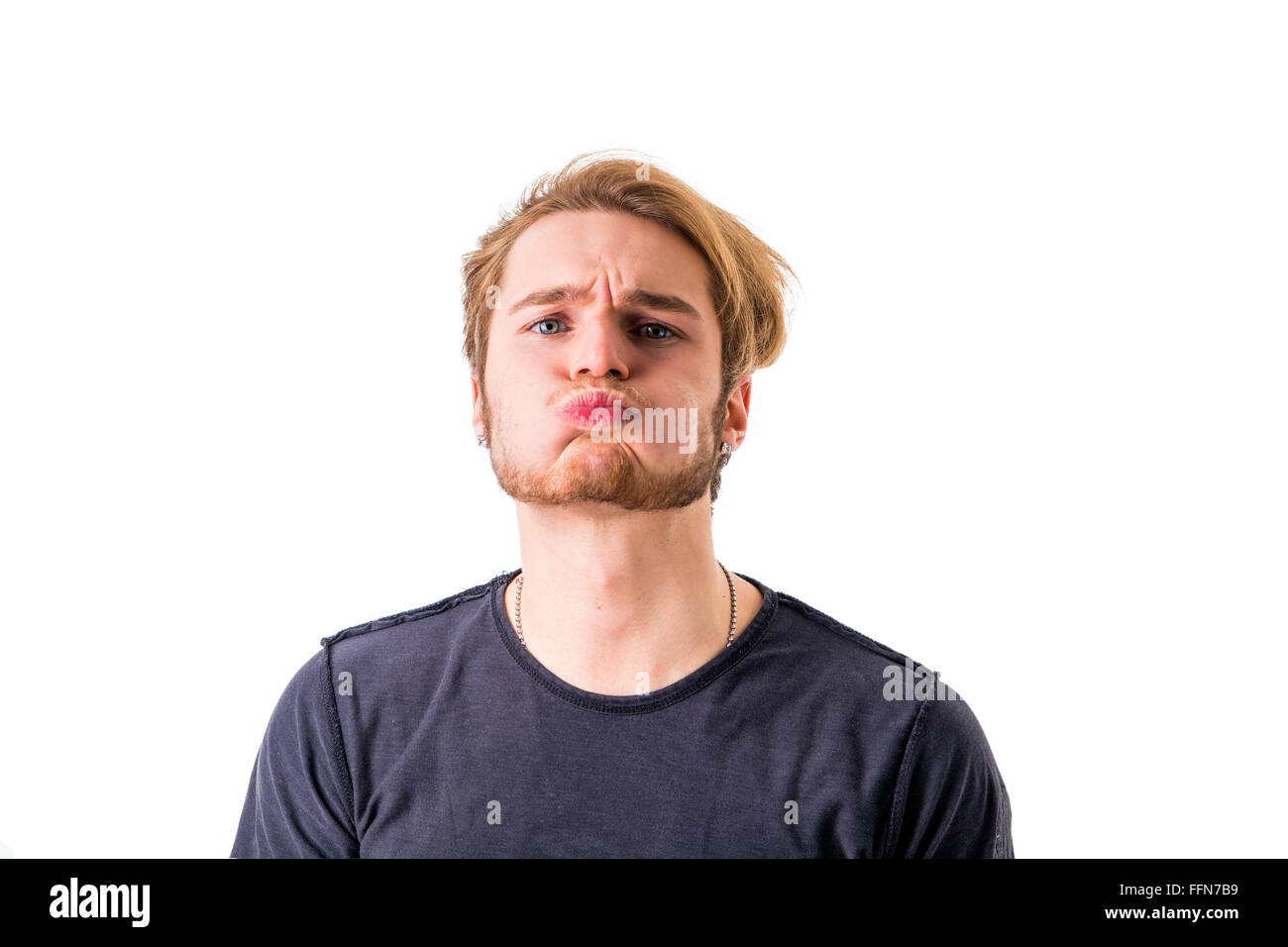 Portrait of young man blowing lips while looking at camera. studio shot ...