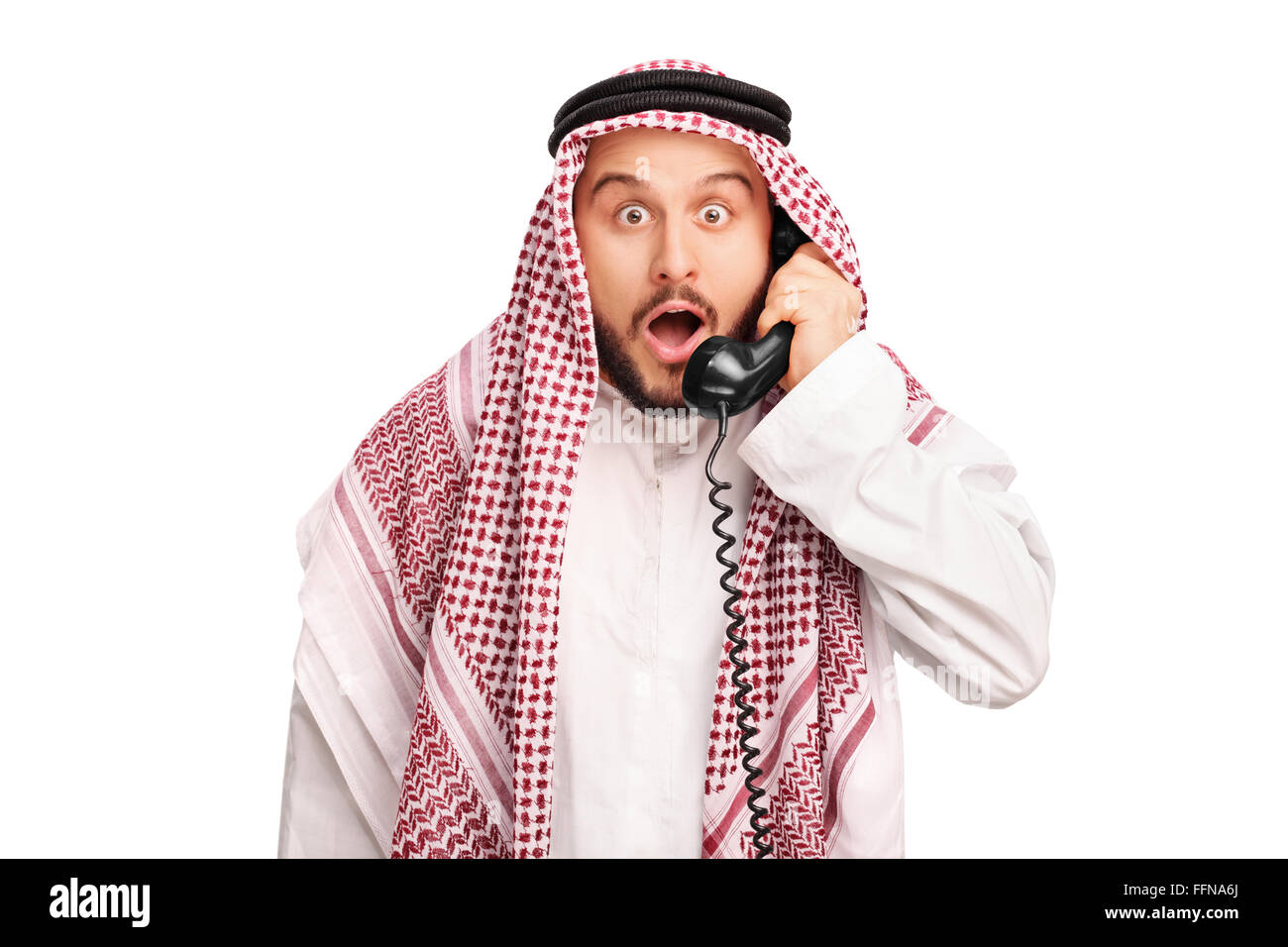 Studio shot of a surprised young Arab speaking on telephone isolated o ...