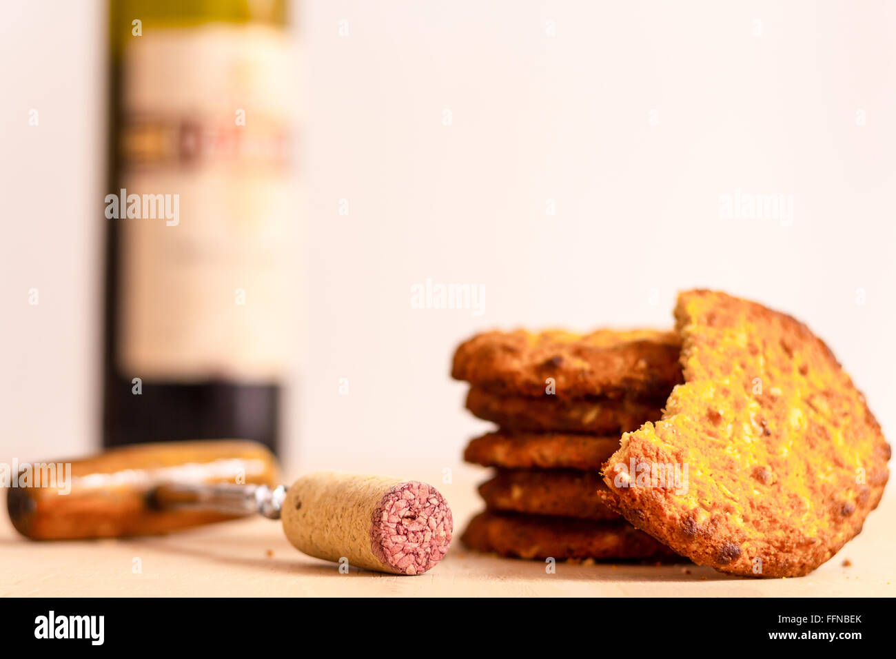 An open bottle of wine with a stack of biscuits and a corkscrew Stock ...