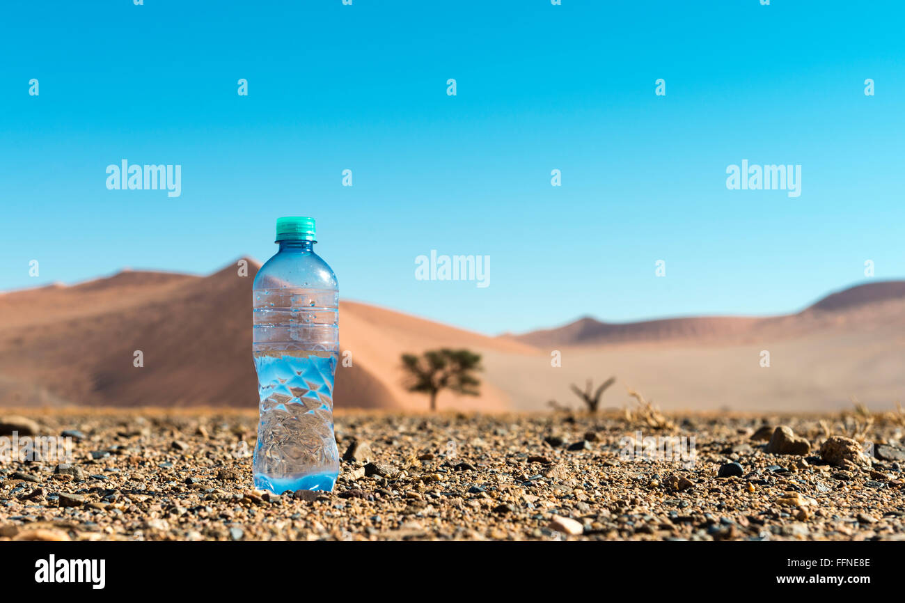 Bottle of water in the middle of the Desert (low angle shot) with dunes ...