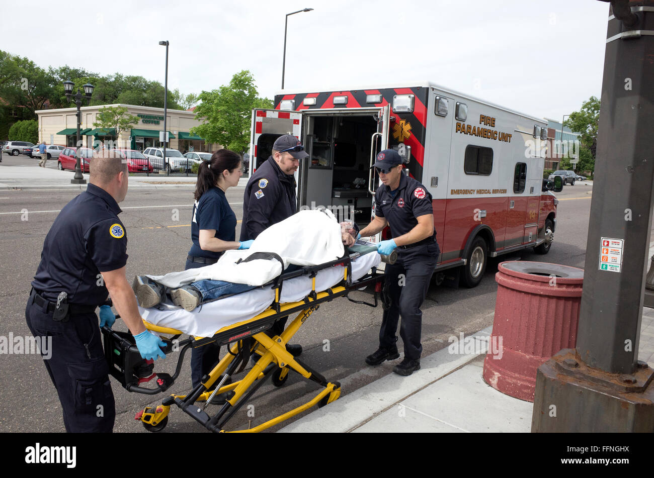 Paramedics rolling strapped down patient into emergency transport ...