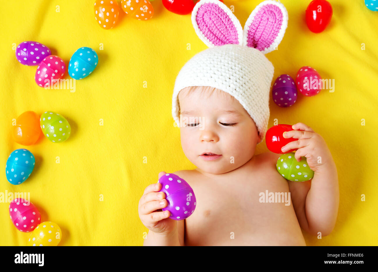 Baby boy in bunny hat lying on yellow blanket with easter eggs Stock ...