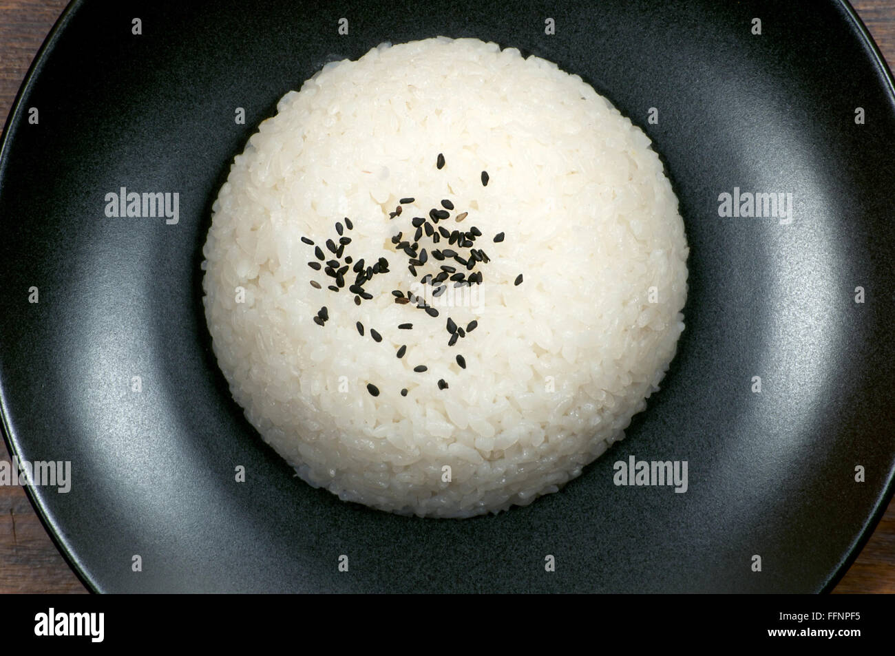 Portion of rice on the black plate close up top view with sesame Stock ...