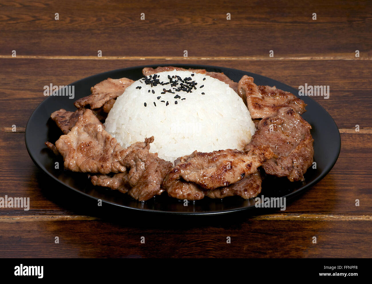 Portion of rice with fried meat on the black plate Stock Photo - Alamy