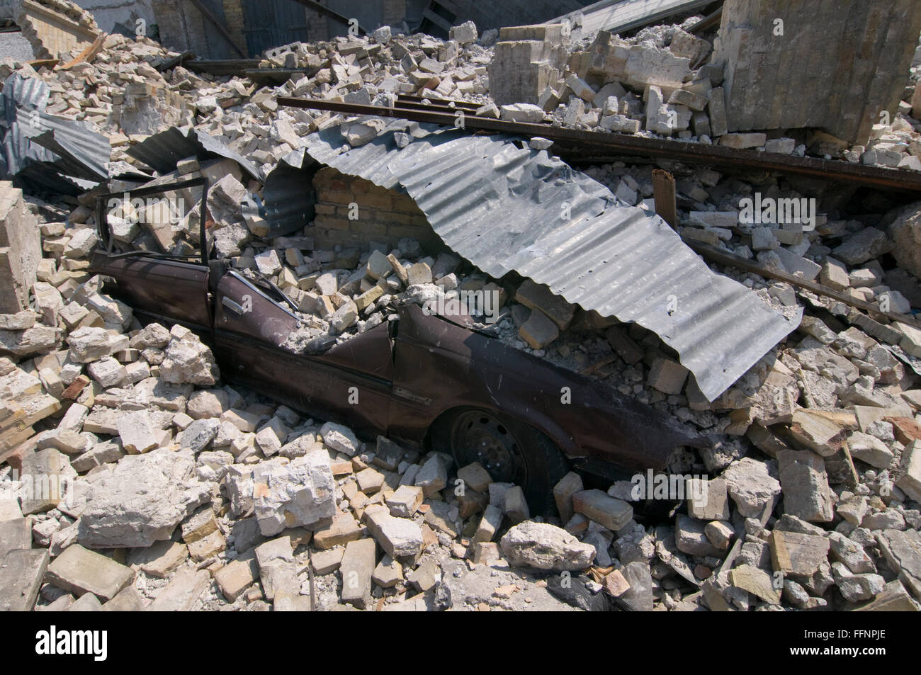 A crushed car under rubble of a building that collapsed after a 7.0 ...