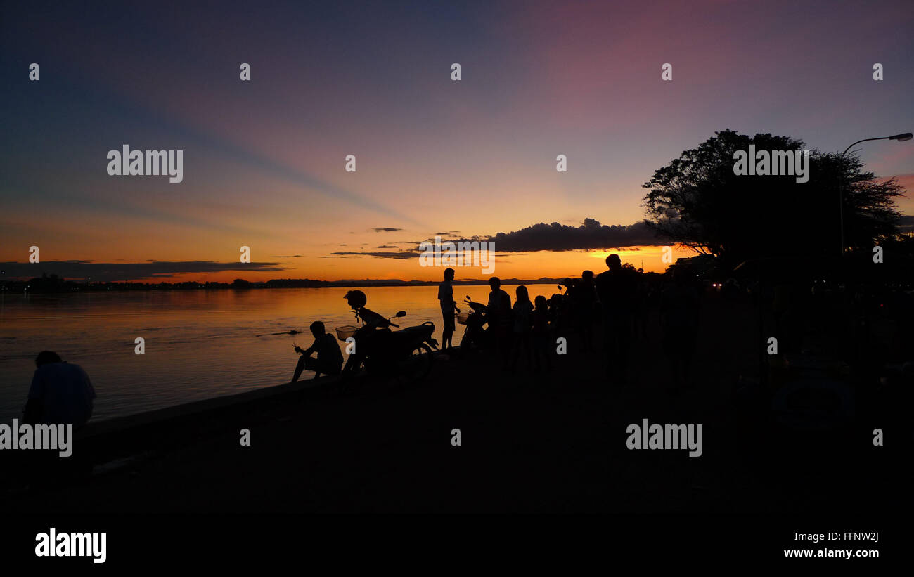 Scene with silhouettes along Mekong River at sunset in Vientiane, Laos ...