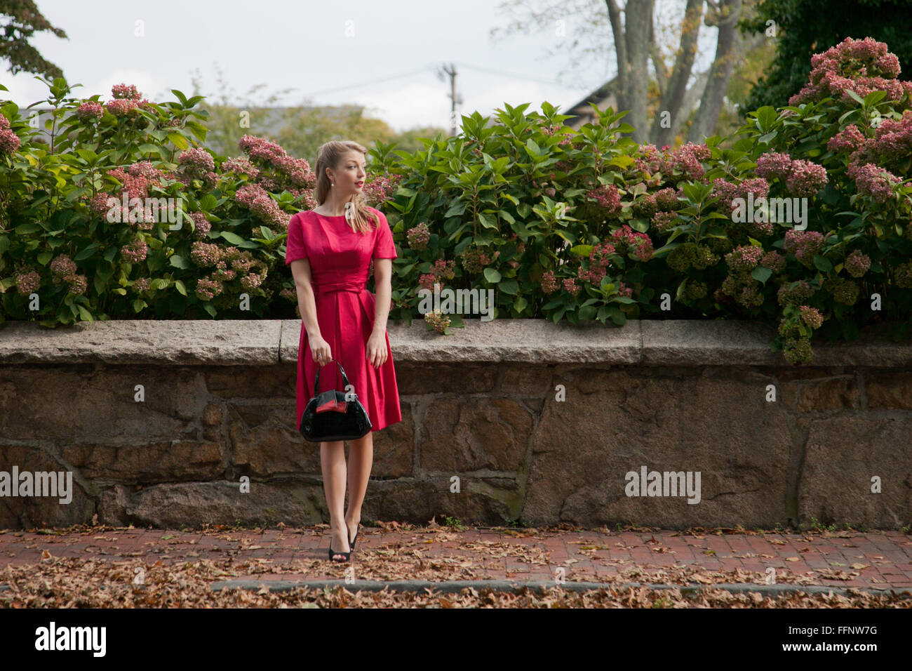 Beautiful blond woman in red dress with a vintage appearance waiting on ...