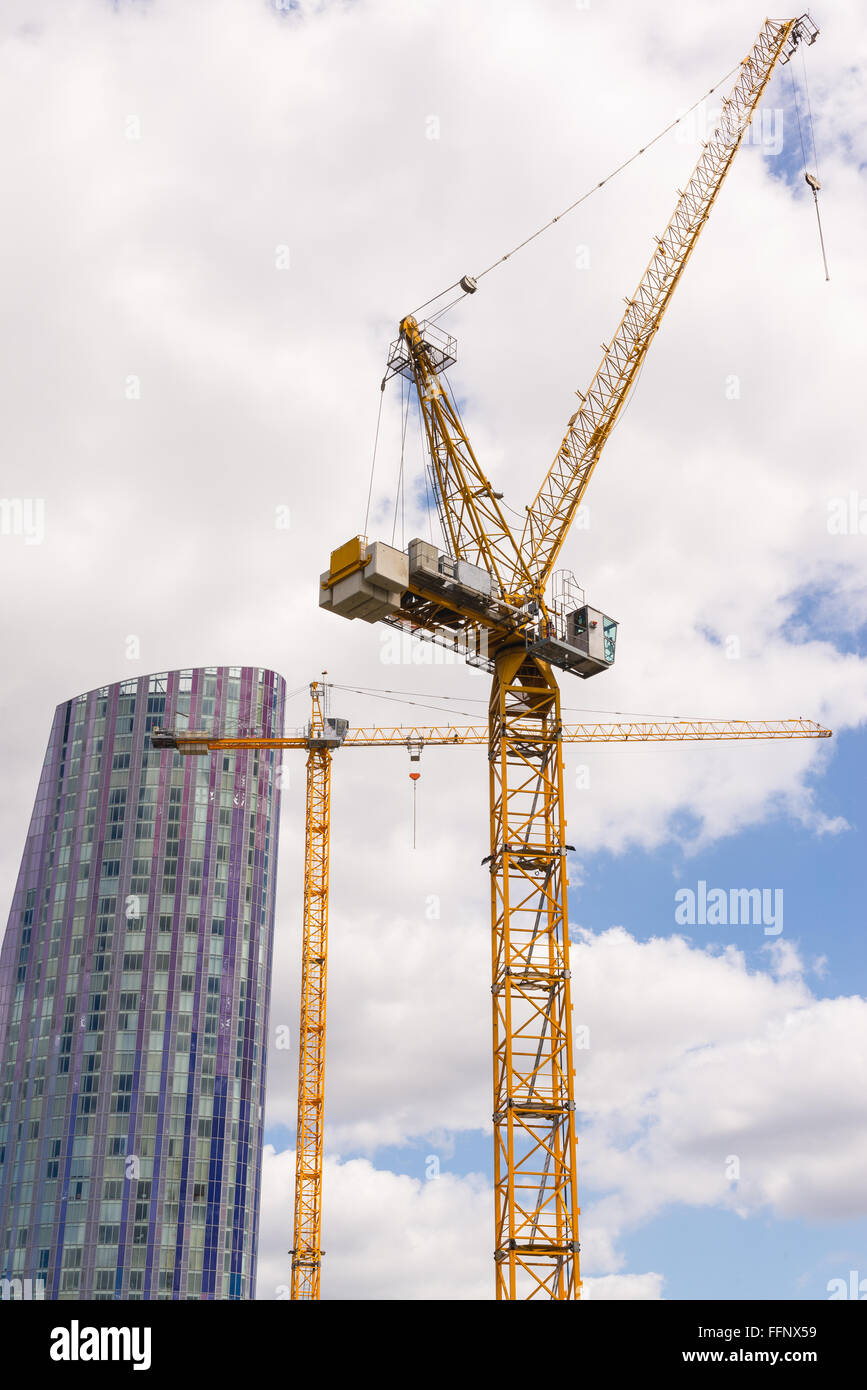 Two big construction cranes with skyscraper and cloudy sky in the ...