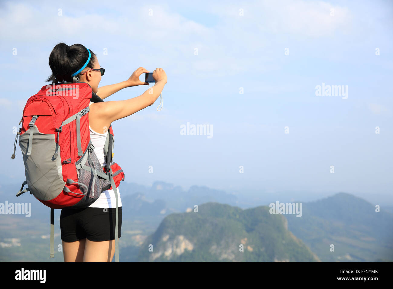 young woman backpacker taking photo with camera on mountain peak Stock ...