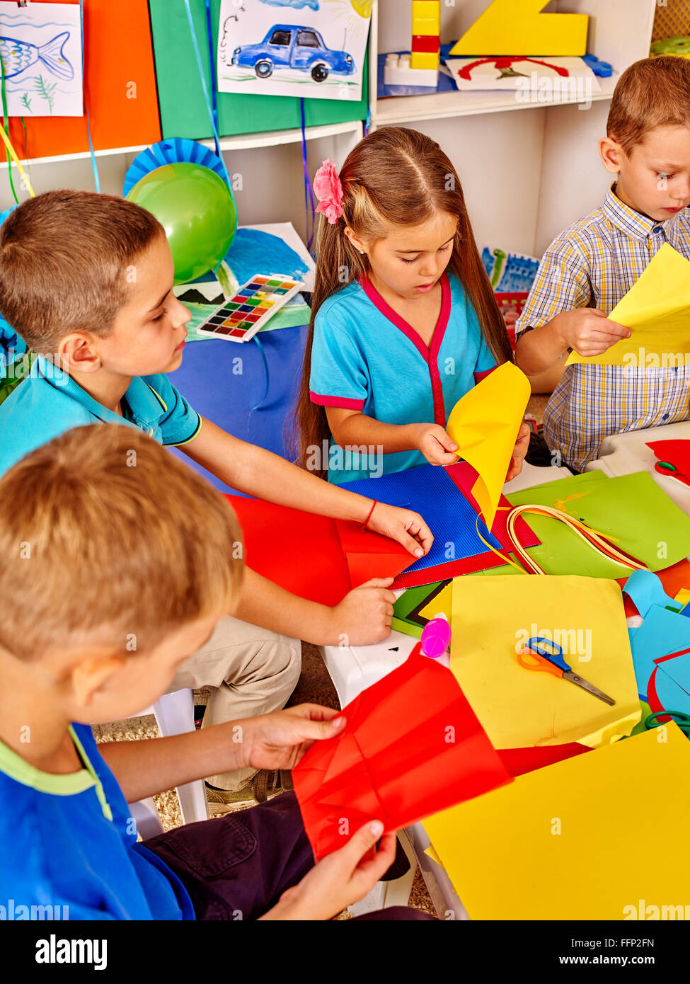 Kids holding colored paper on lesson table in kindergarten Stock Photo ...