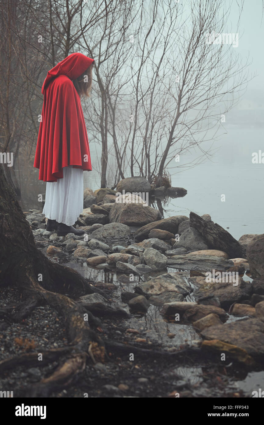 Dark and sad portrait of a red hooded woman . Dream and surreal colors ...
