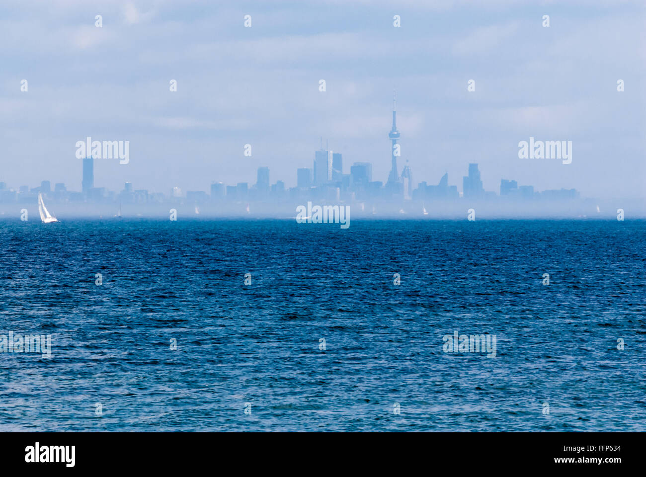 Toronto city skyline from across wavy blue rippled water with sailboat ...