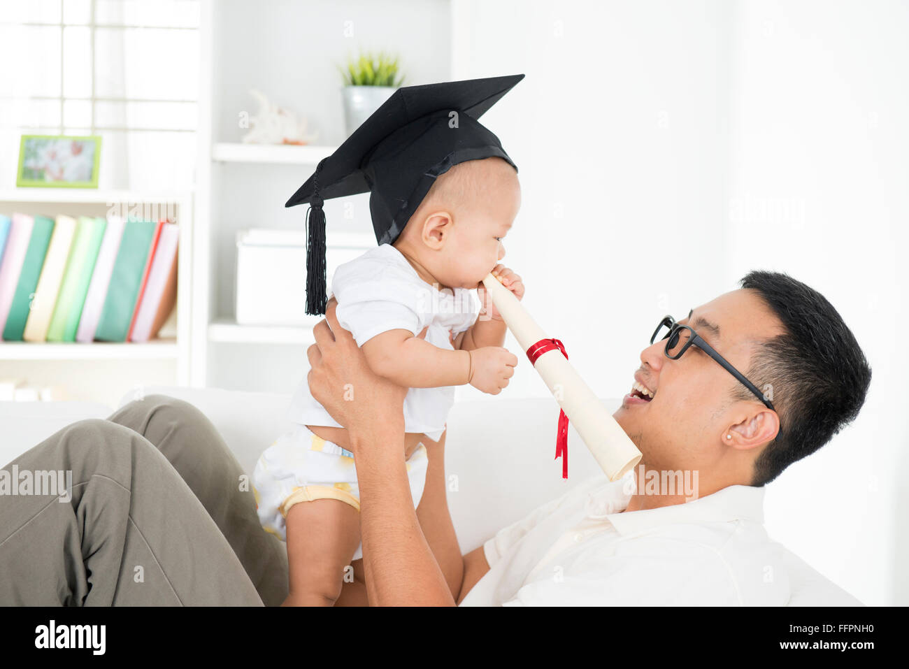 Baby with graduation cap holding certificate with father. Parent and ...
