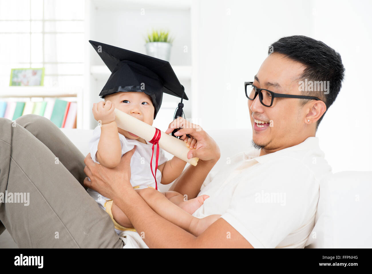 Asian family lifestyle at home. Baby with graduation cap holding ...