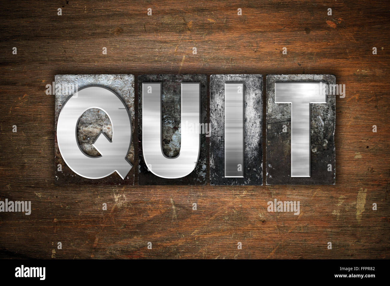 The word "Quit" written in vintage metal letterpress type on an aged ...