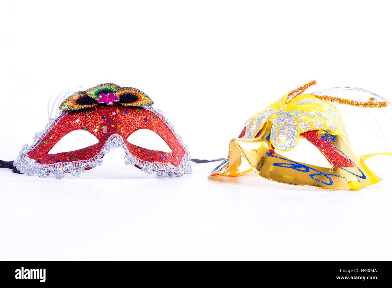 Two masks placed on white, one red and the other golden Stock Photo - Alamy