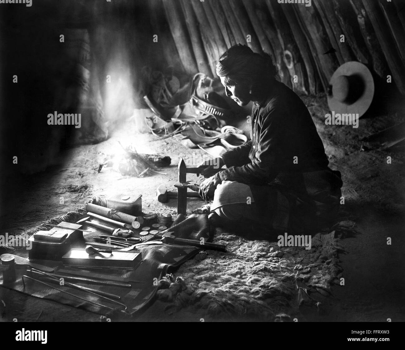 NAVAJO SILVERSMITH, c1915. /nA Navajo man shaping silver near a fire ...