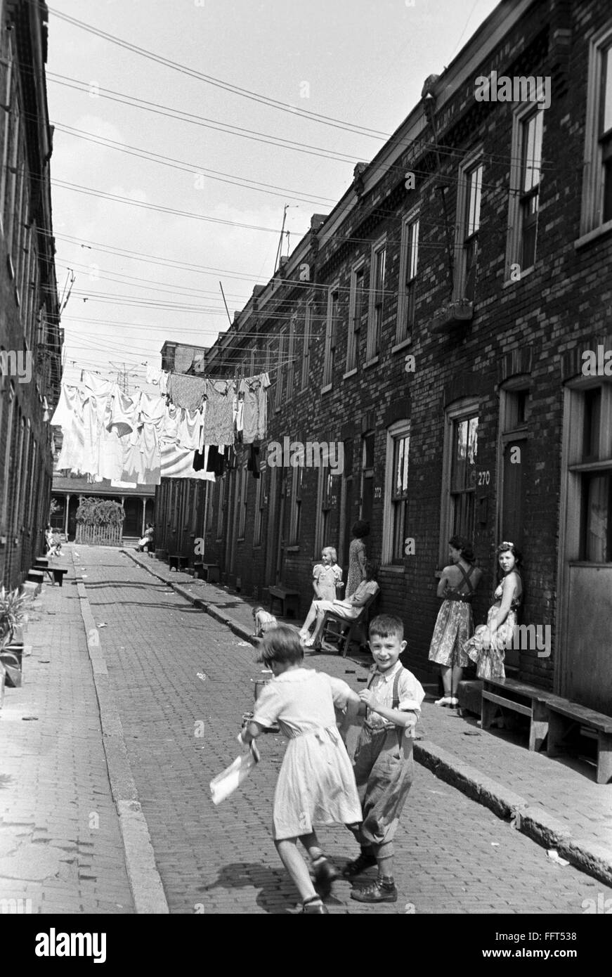 ROW HOUSES, 1938. /nWomen and children in front of a row of low-income ...