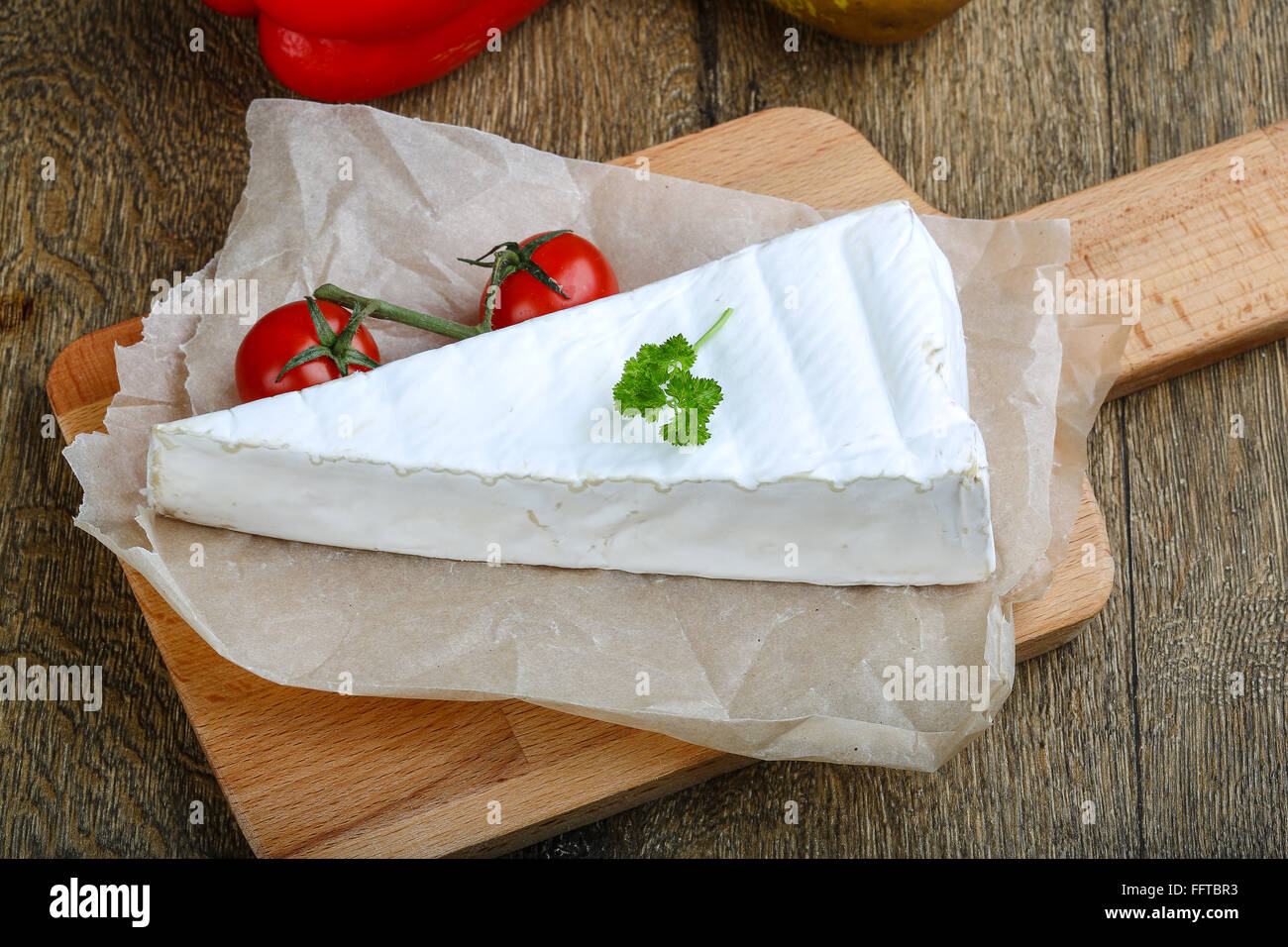Brie cheese triangle with tomato and parsley Stock Photo - Alamy