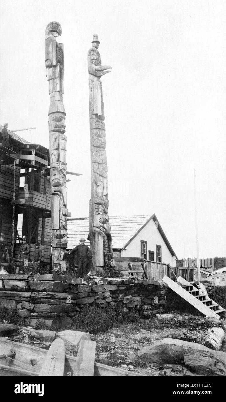 ALASKA: TOTEM POLES, c1887. /nA man standing next to two totem poles ...
