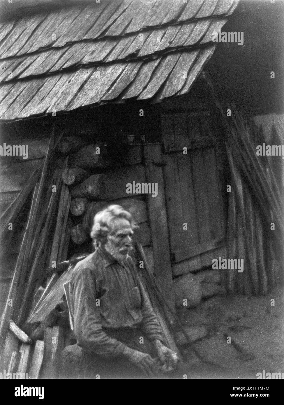 LOG CABIN, c1930. /nAn old man sitting in front of a log cabin in rural ...