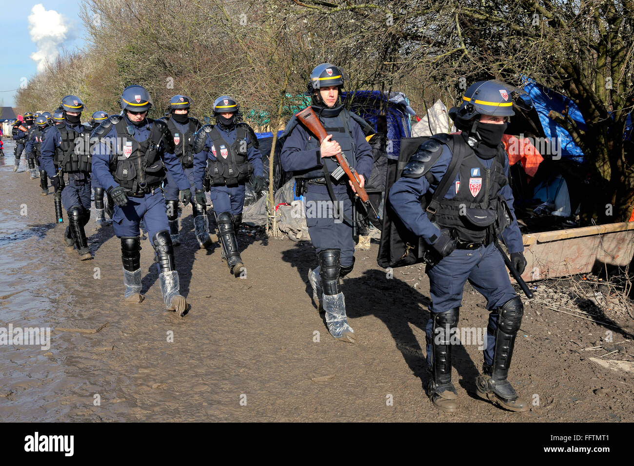 Armed french riot police walk through the refugee camp of Grande-Synthe ...
