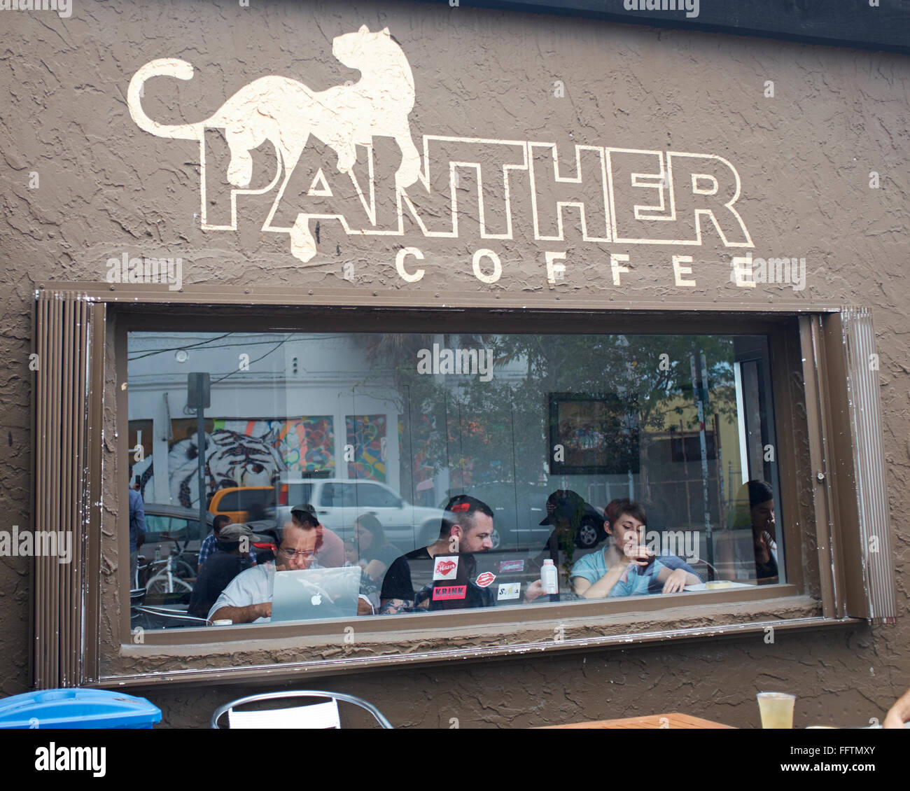 Exterior view of Panther Coffee in Miami with people sitting inside ...