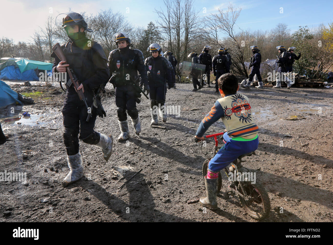Armed french riot police walk through the refugee camp of Grande-Synthe ...