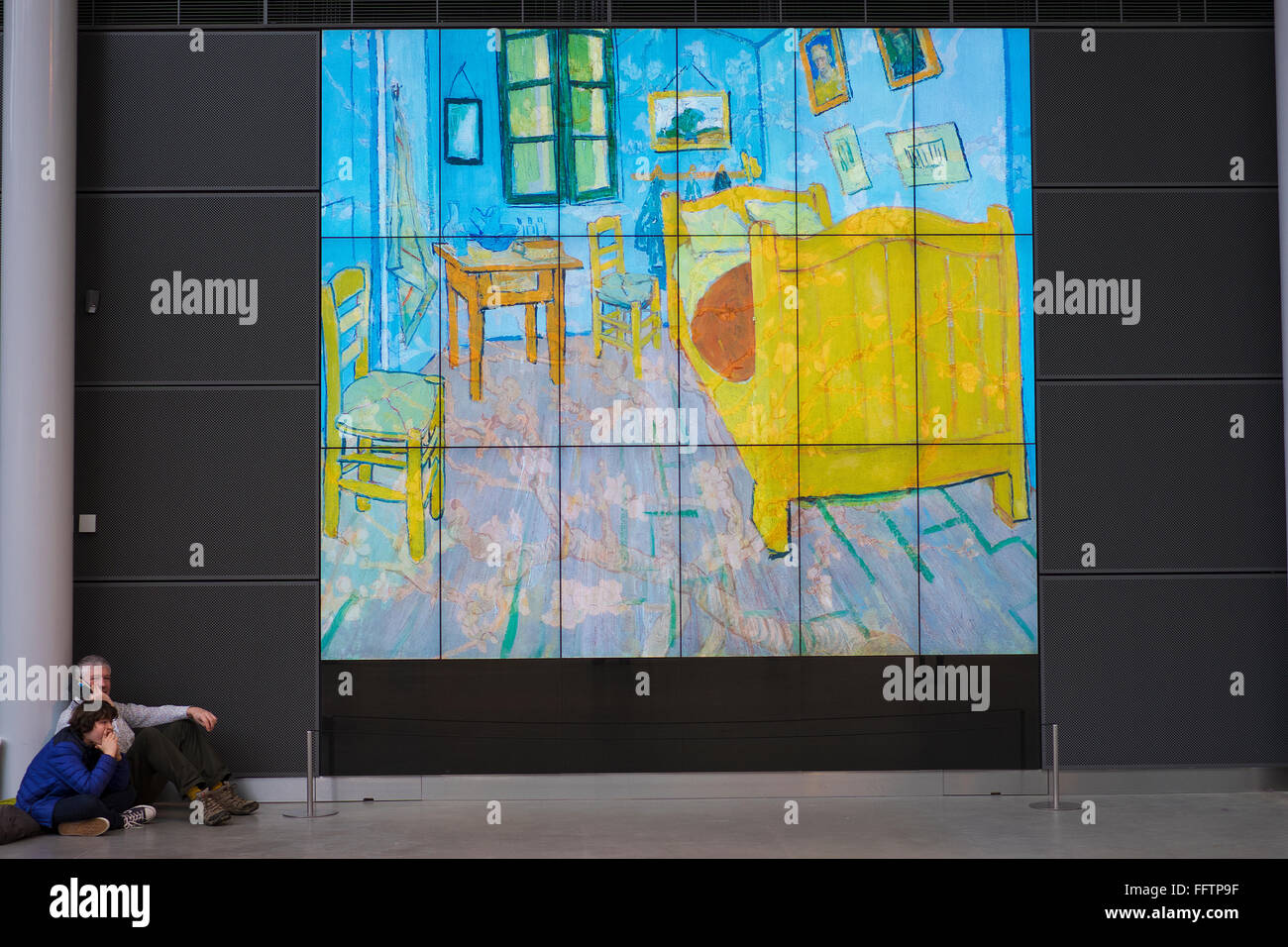 Visitors sit in front of a giant screen featuring The Bedroom by ...