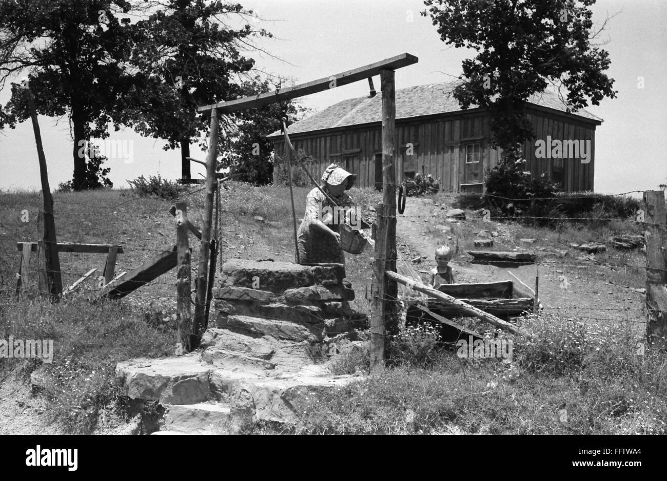 TENANT FARMER, 1939. /nA tenant farmer drawing water at a well on a ...