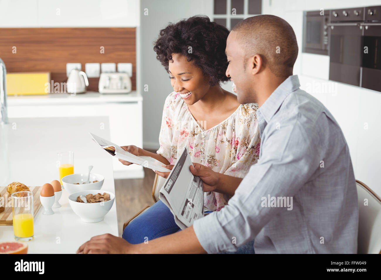 Smiling couple reading magazine and documents during breakfast Stock ...