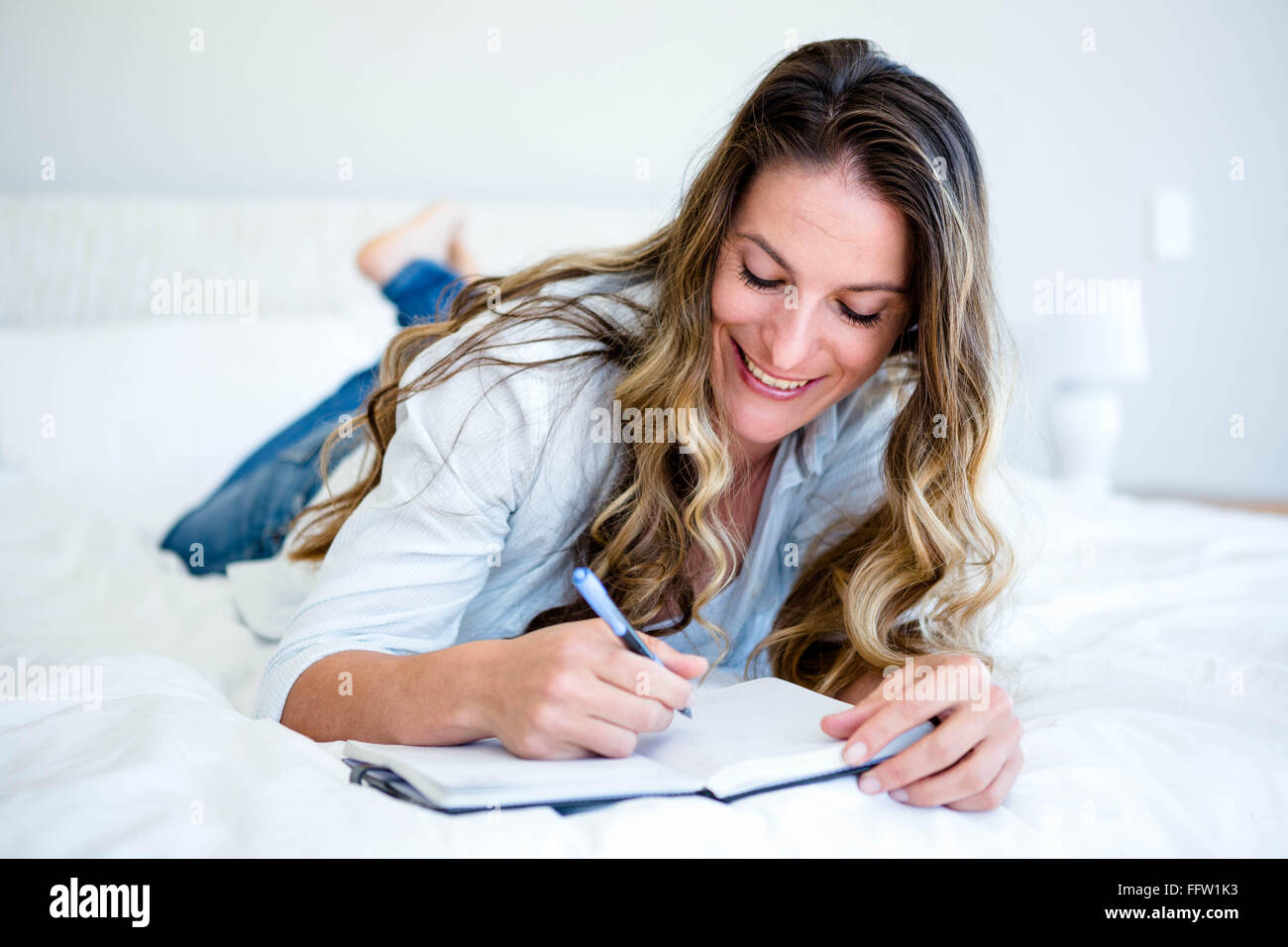 woman lying on her bed writing in a book Stock Photo - Alamy