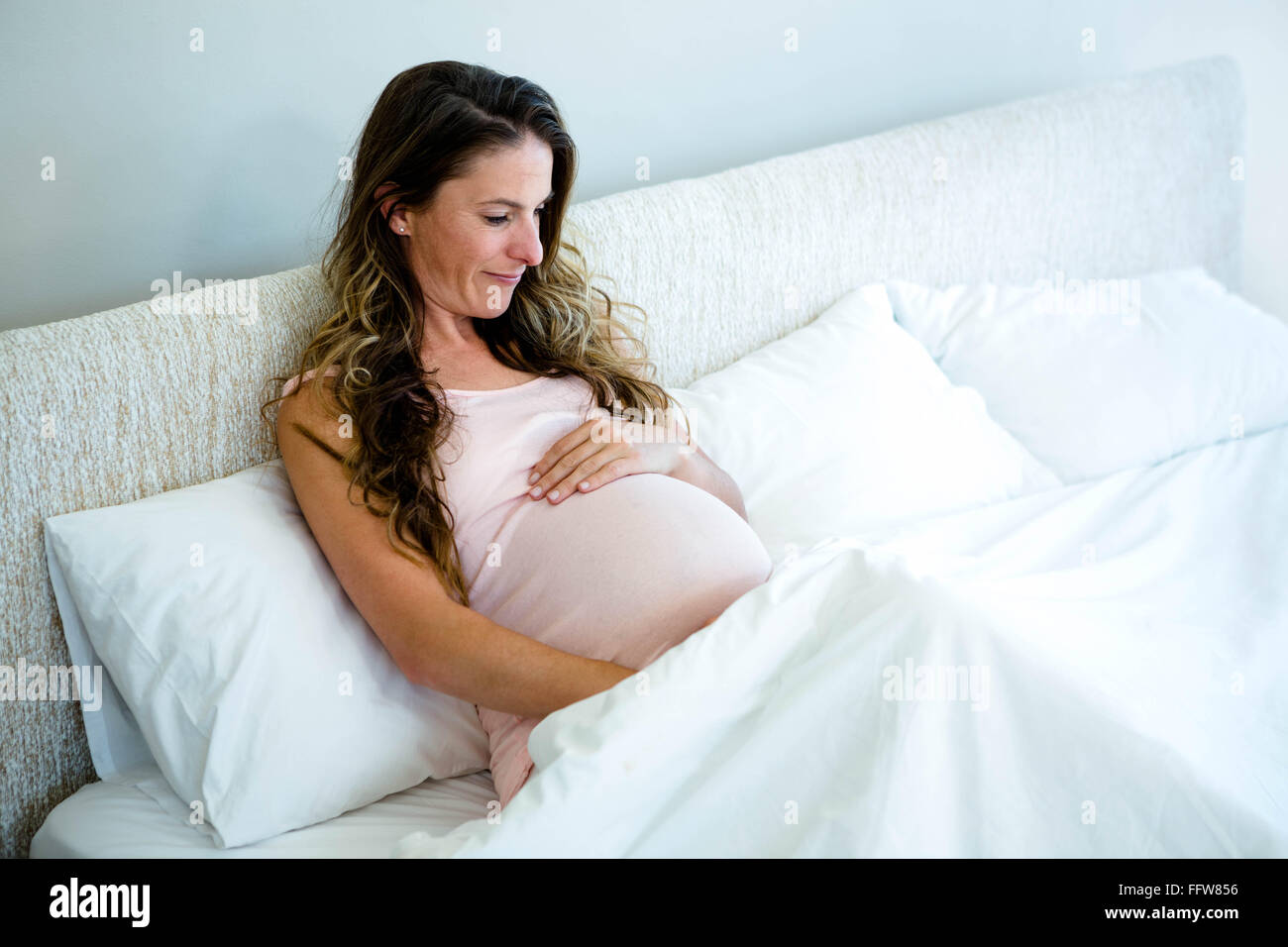 Pregnant woman in bed holding hi-res stock photography and images - Alamy