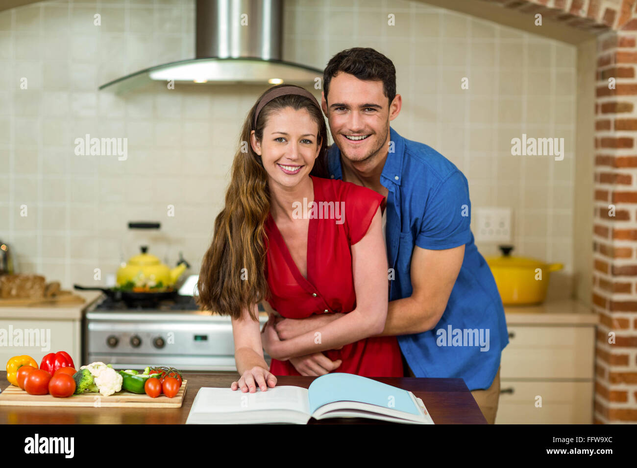 Couple embracing while checking the recipe book Stock Photo - Alamy