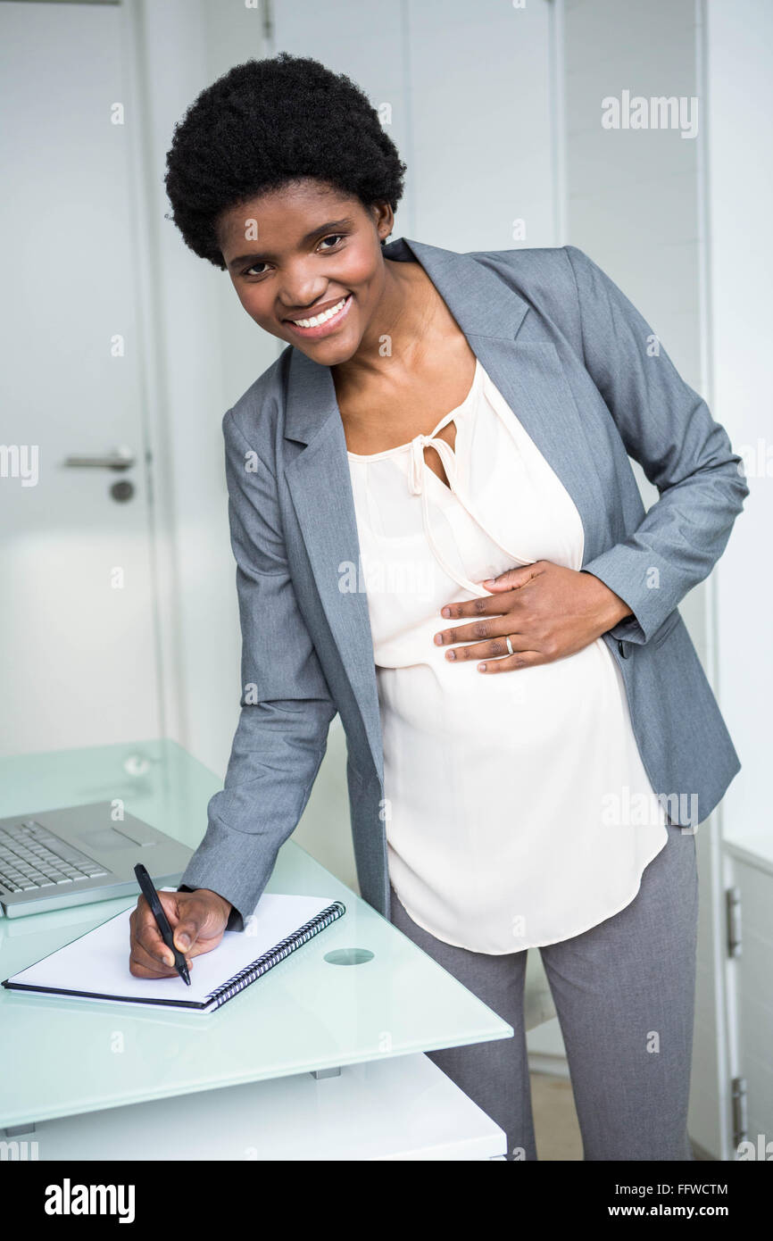 Pregnant businesswoman writing on notebook Stock Photo - Alamy