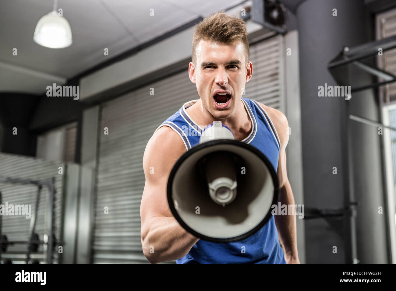 Muscular trainer shouting on megaphone Stock Photo - Alamy