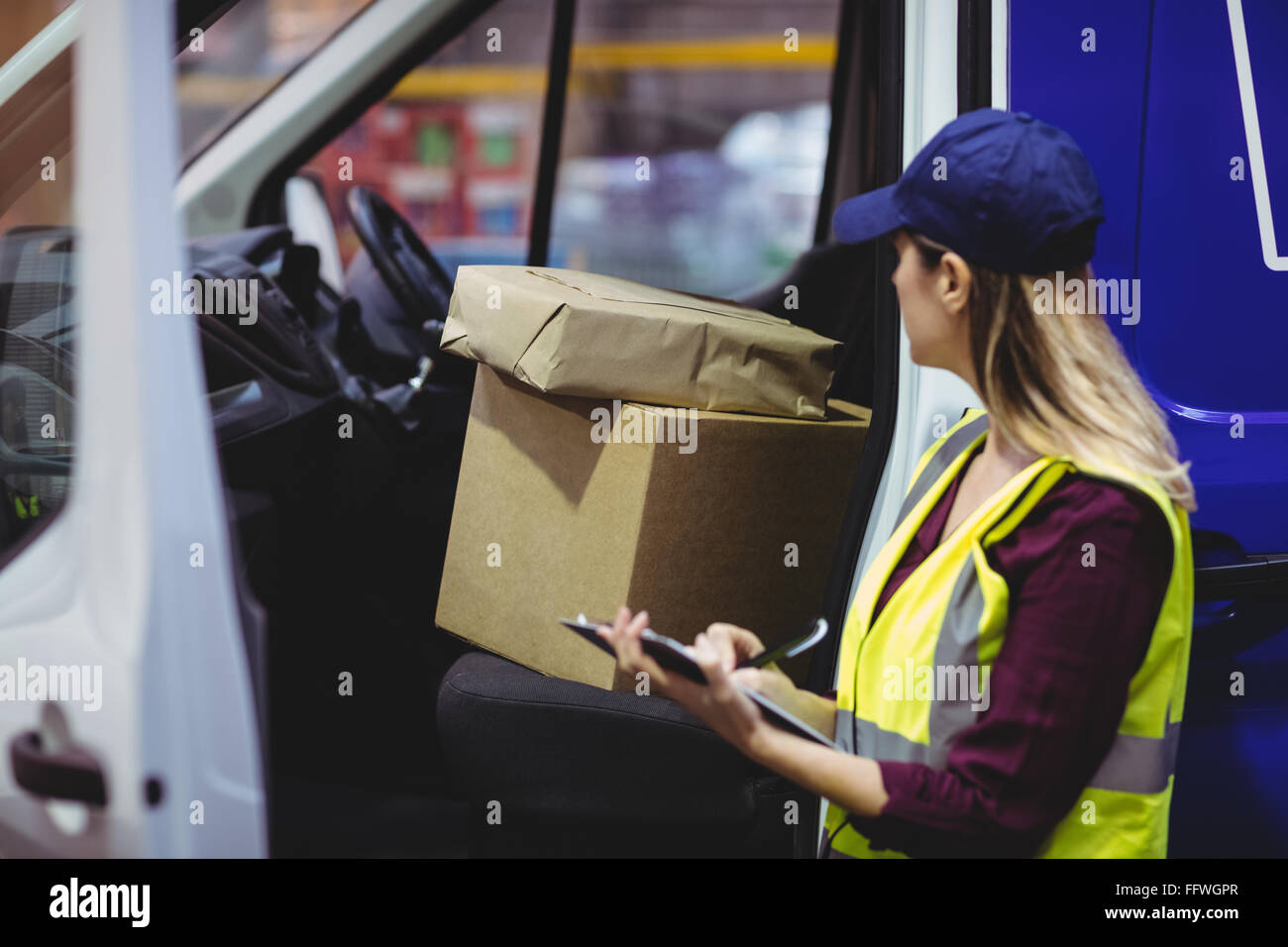Delivery driver checking his list on clipboard Stock Photo - Alamy