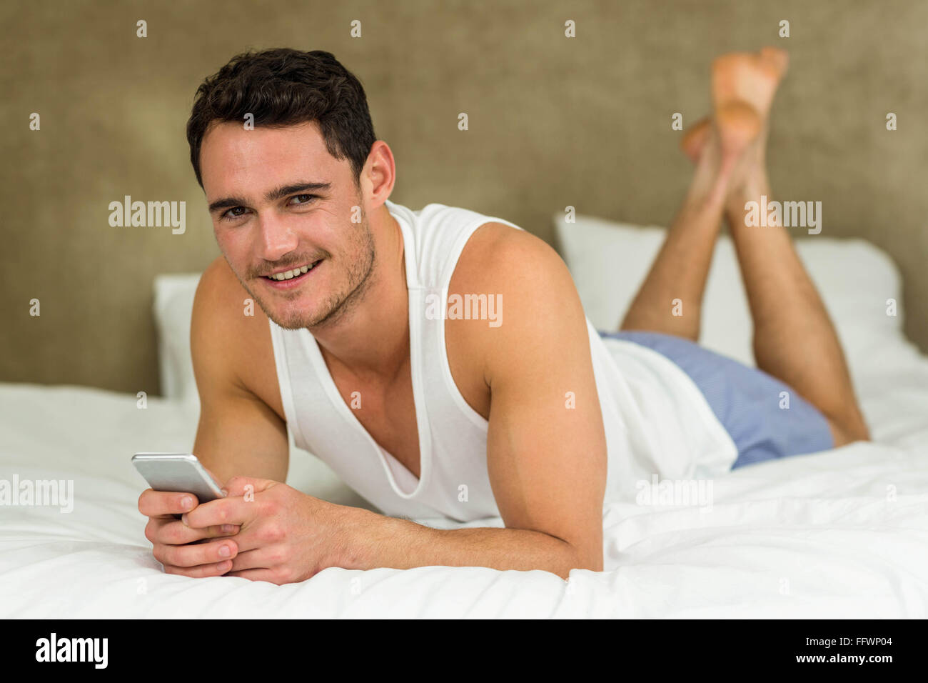 Young man lying on bed with his phone Stock Photo - Alamy