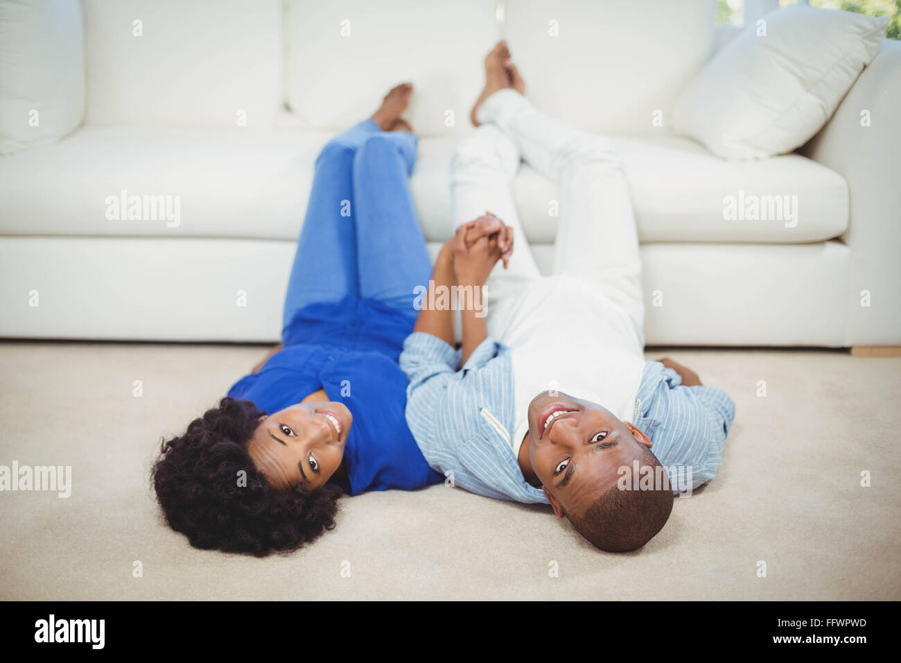 Happy couple lying on the floor Stock Photo - Alamy
