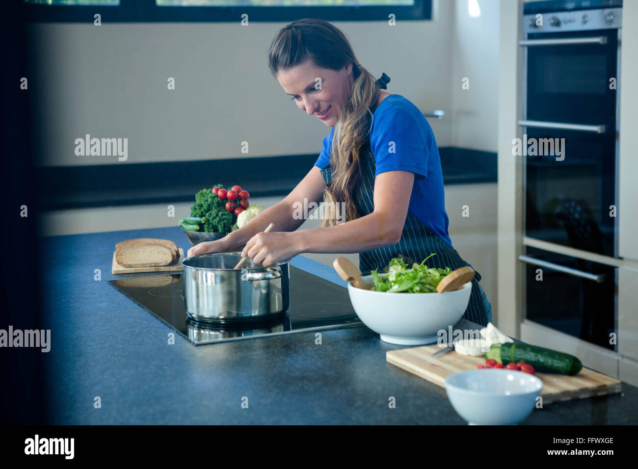 smiling woman cooking on the stove top Stock Photo - Alamy