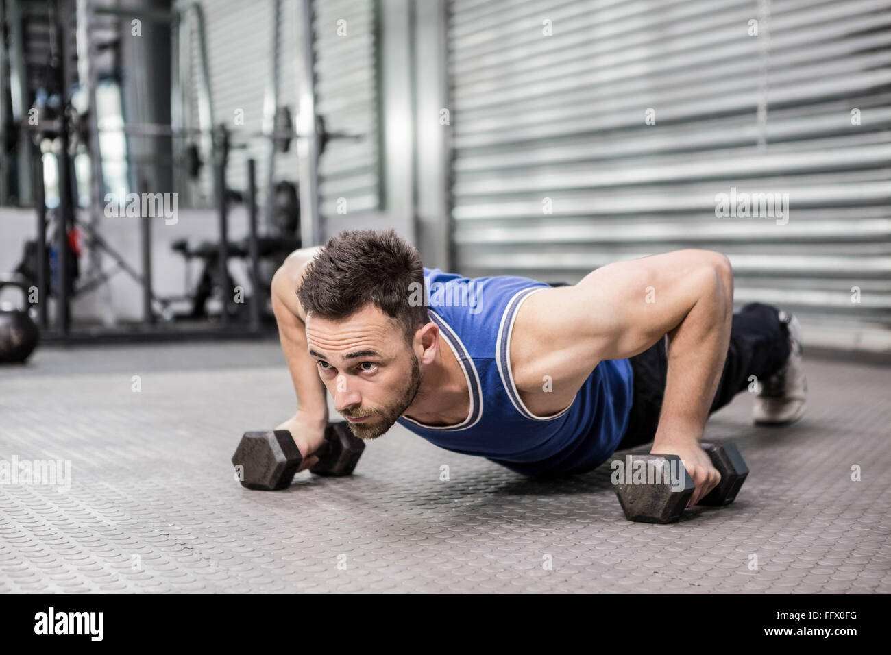 Muscular man doing push up with dumbbells Stock Photo - Alamy