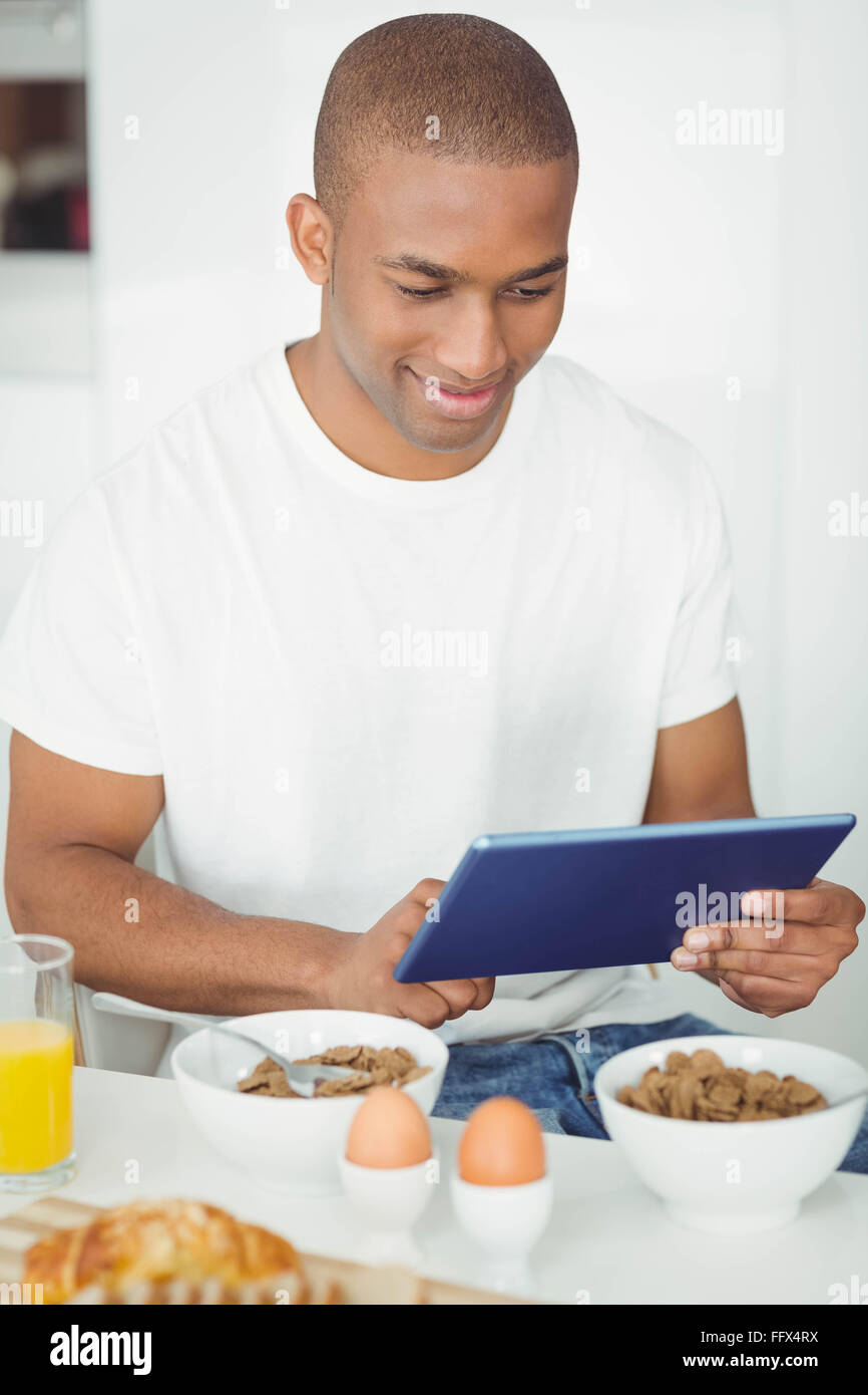 Young man using tablet and eating breakfast in kitchen Stock Photo - Alamy