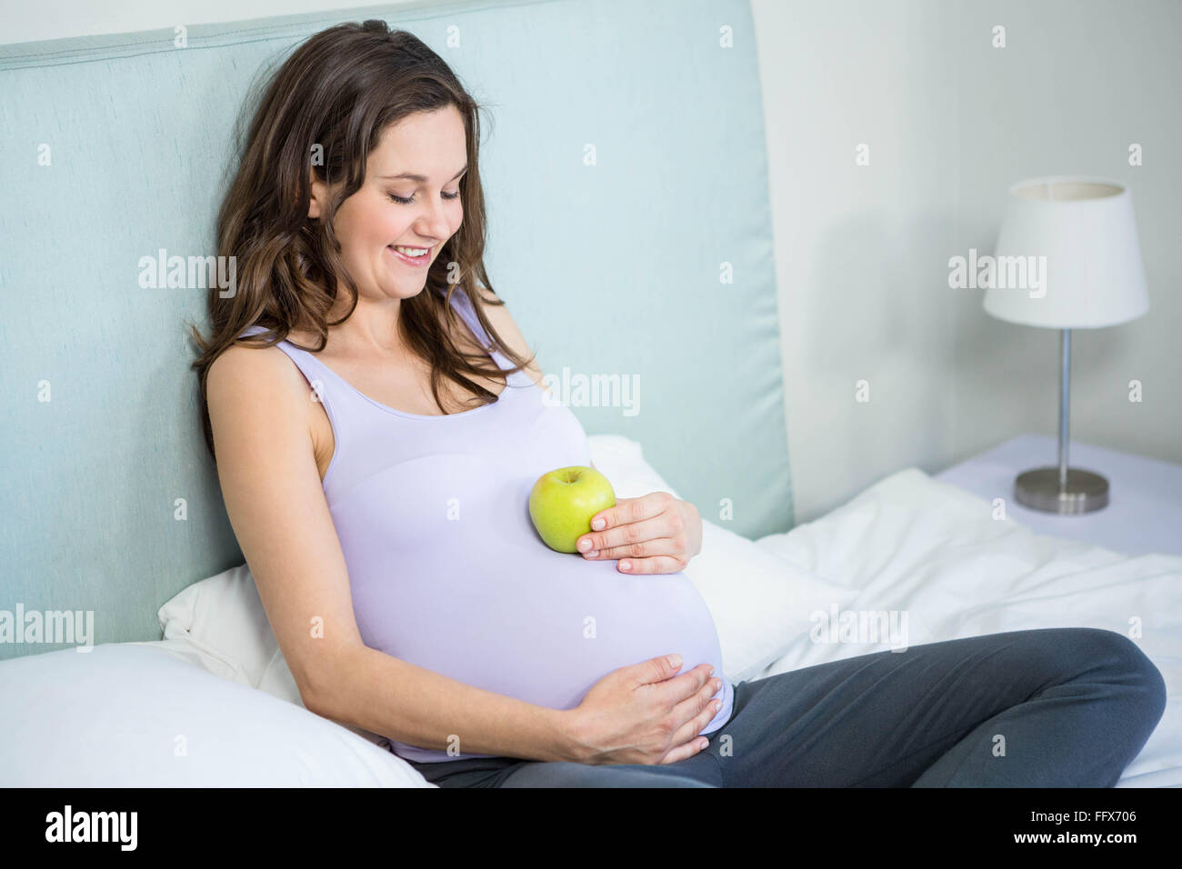 Pregnant woman holding an apple on her bump Stock Photo - Alamy
