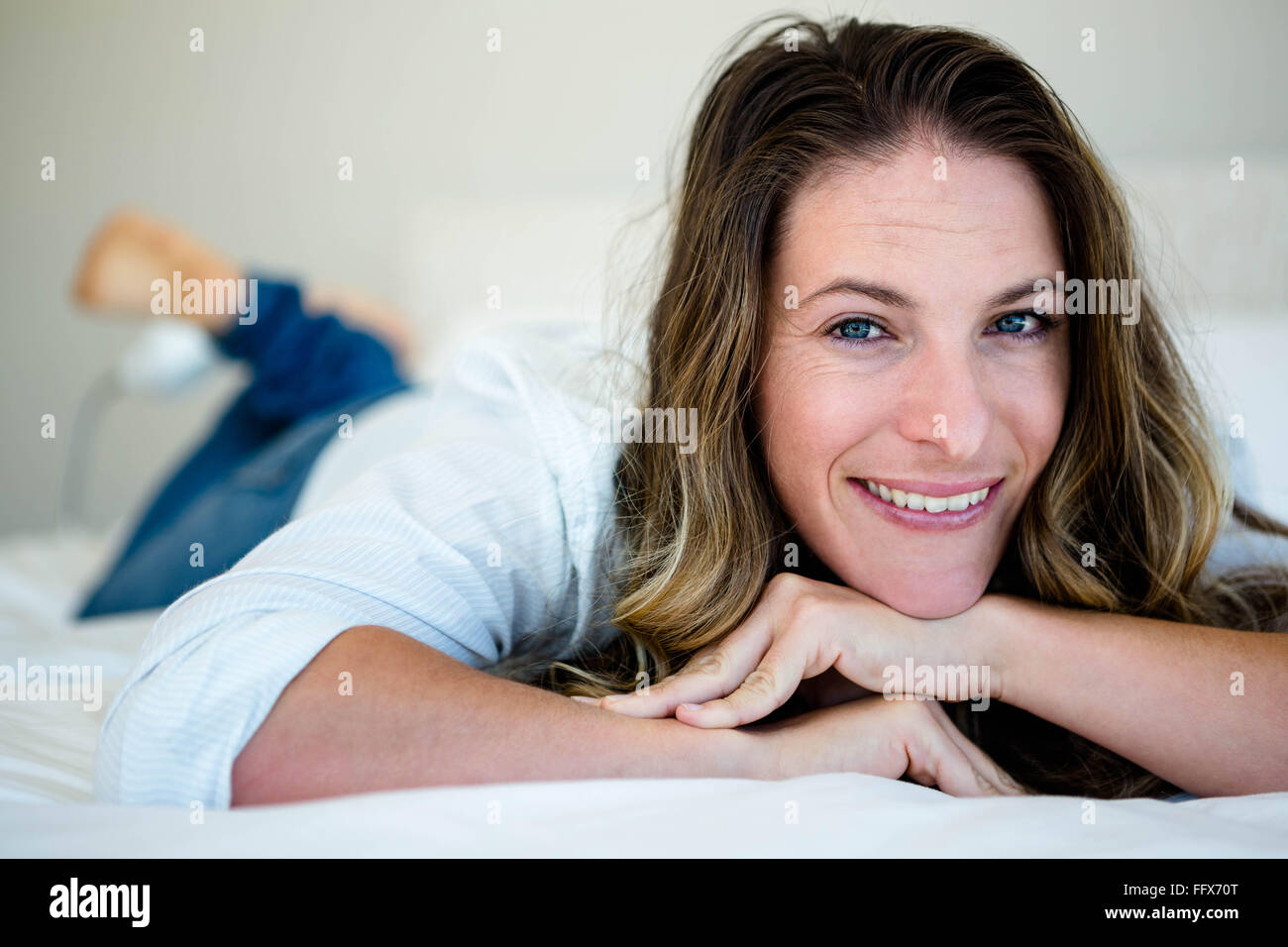 Woman lying on her bed smiling Stock Photo - Alamy