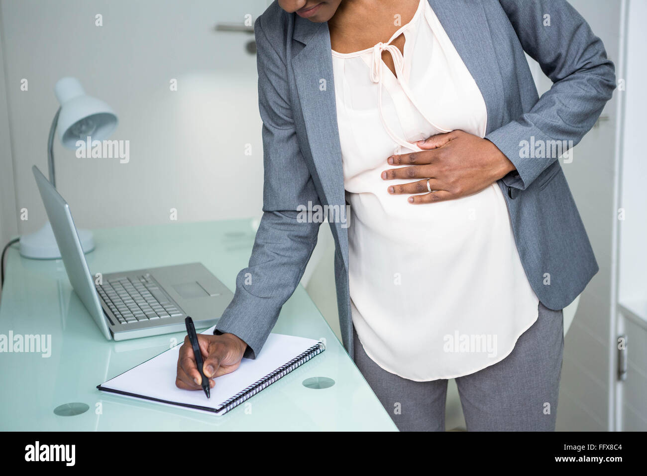 Pregnant businesswoman writing on notebook Stock Photo - Alamy