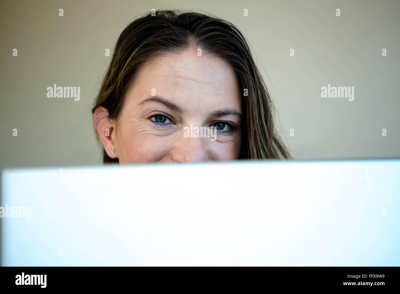 woman looking over the top of her laptop screen Stock Photo - Alamy