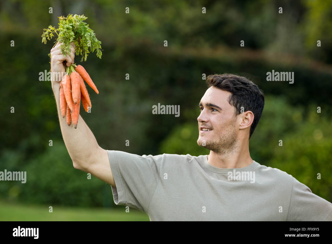 Young man holding bunch of carrots Stock Photo - Alamy