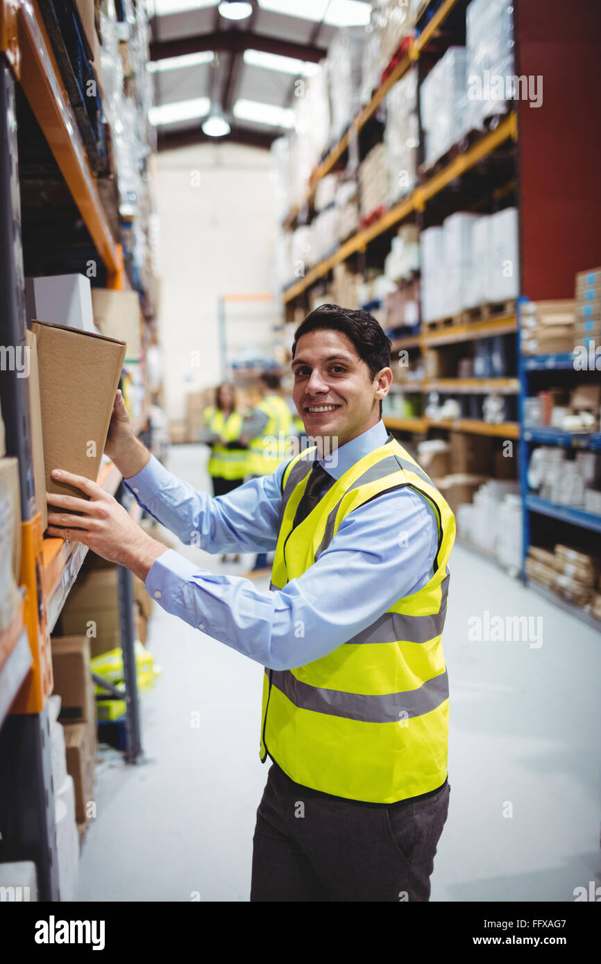 Smiling warehouse worker taking package in the shelf Stock Photo - Alamy