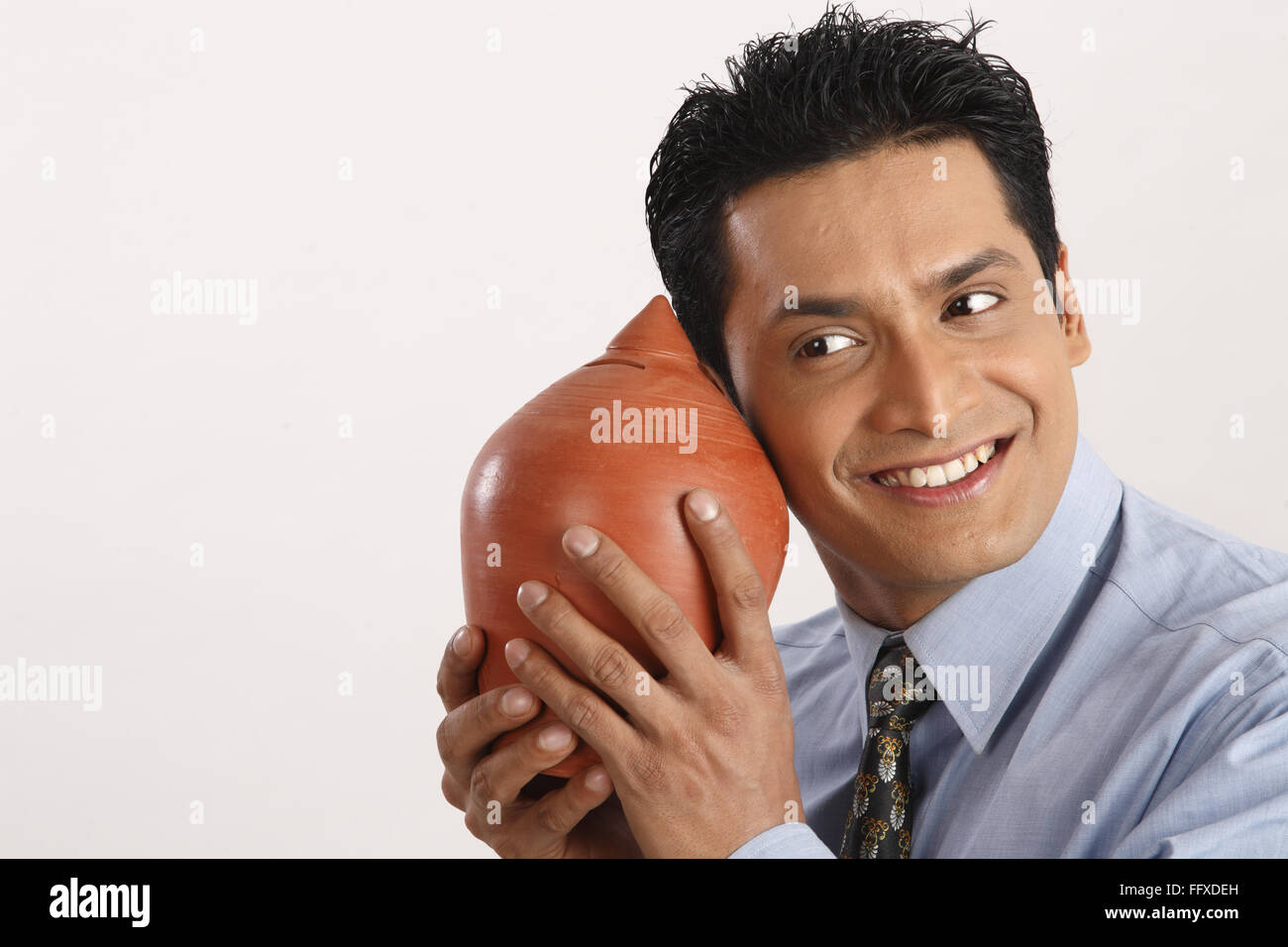 Businessman holding small saving earthen pot in both hands and shaking ...